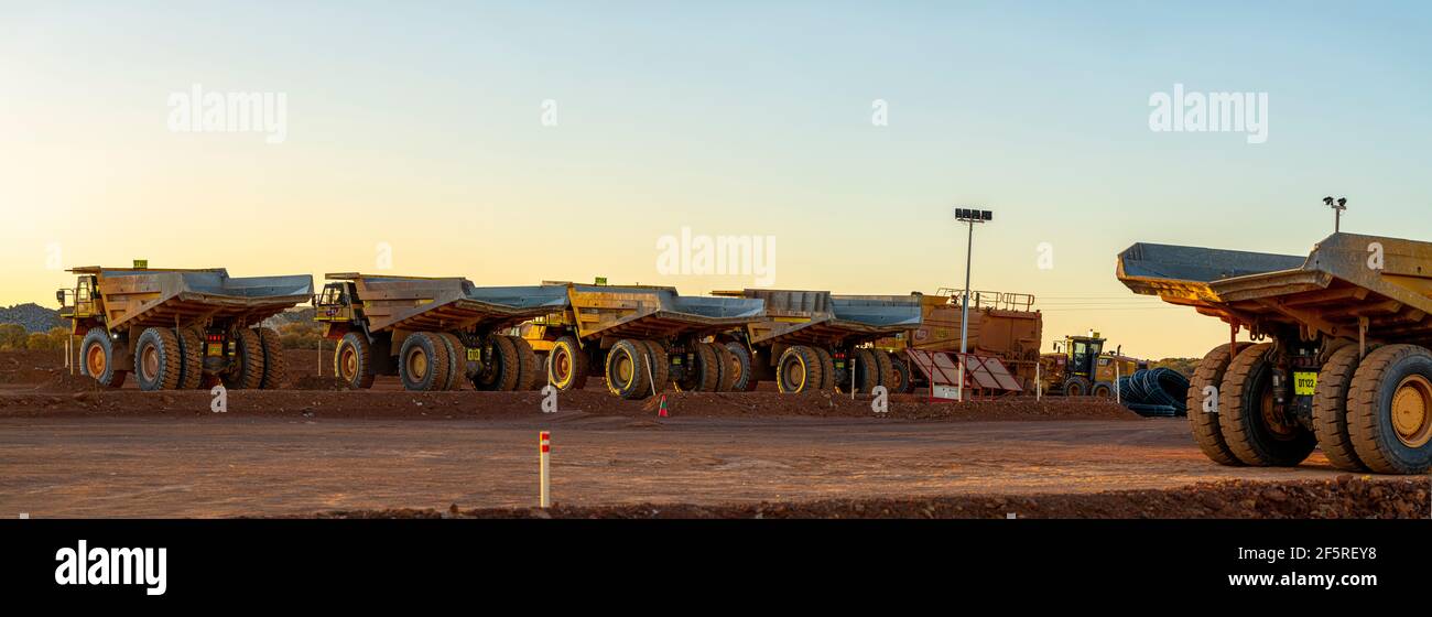Dump trucks lined up on Go Line at sunset in open pit mining area Stock ...
