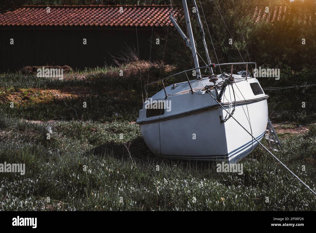 View of an old tilted sailboat with a bare mast without a sail, on its ...