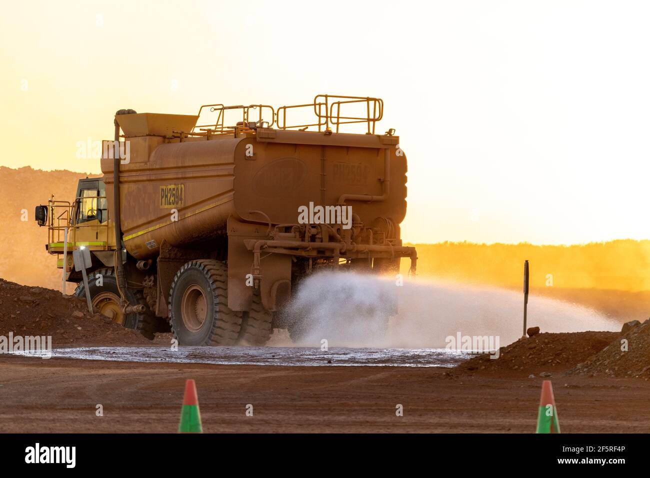Water Cart dampening dusty mining roads at sunset in open pit mining ...