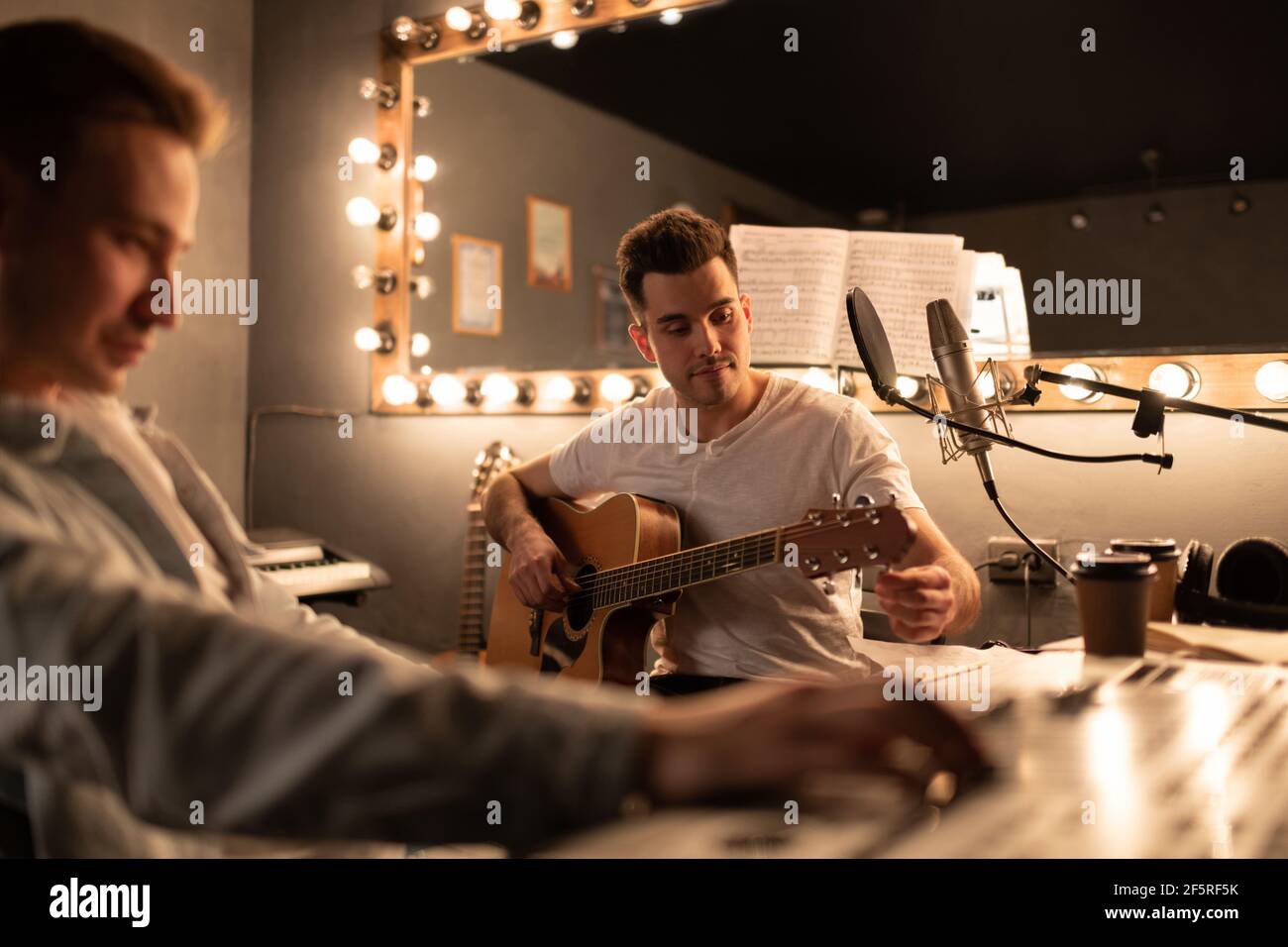 Male guitarist tuning instrument near sound director Stock Photo - Alamy