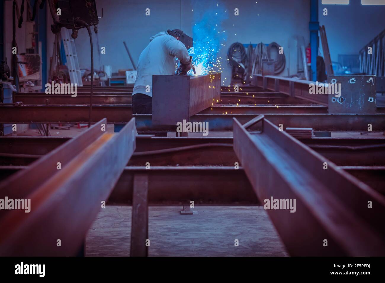 Man with protective face and eye shield welding industrial steel beam ...