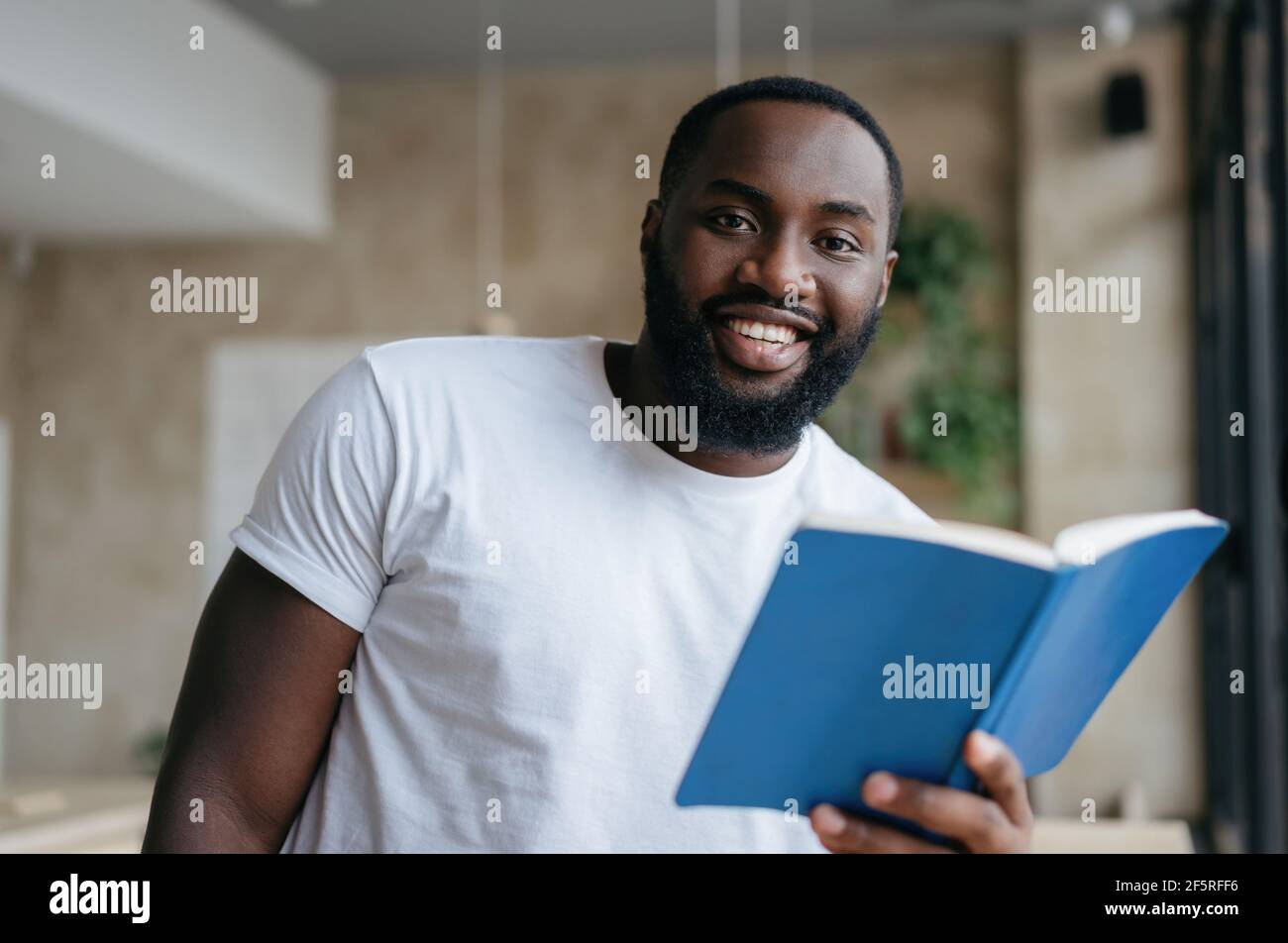Portrait of happy African American man reading a book. Smiling student ...
