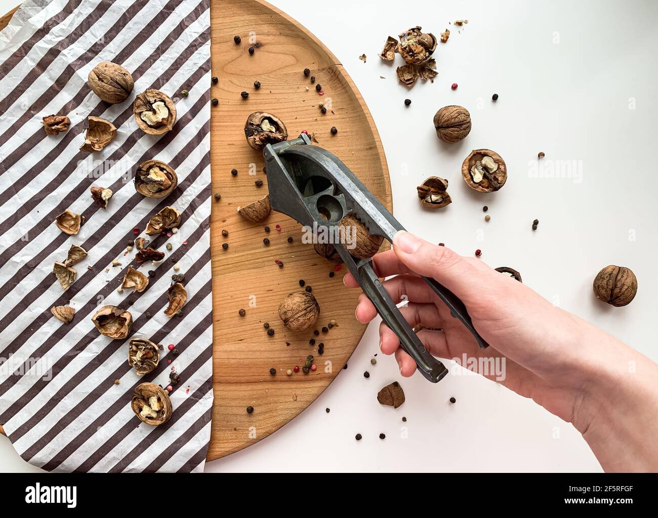 Young woman is cracking walnut on a wooden board and white background ...