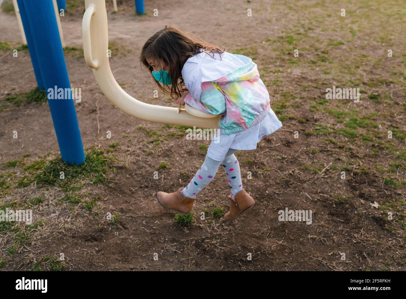 Girl wearing face mask playing at playground in dress and boots Stock ...