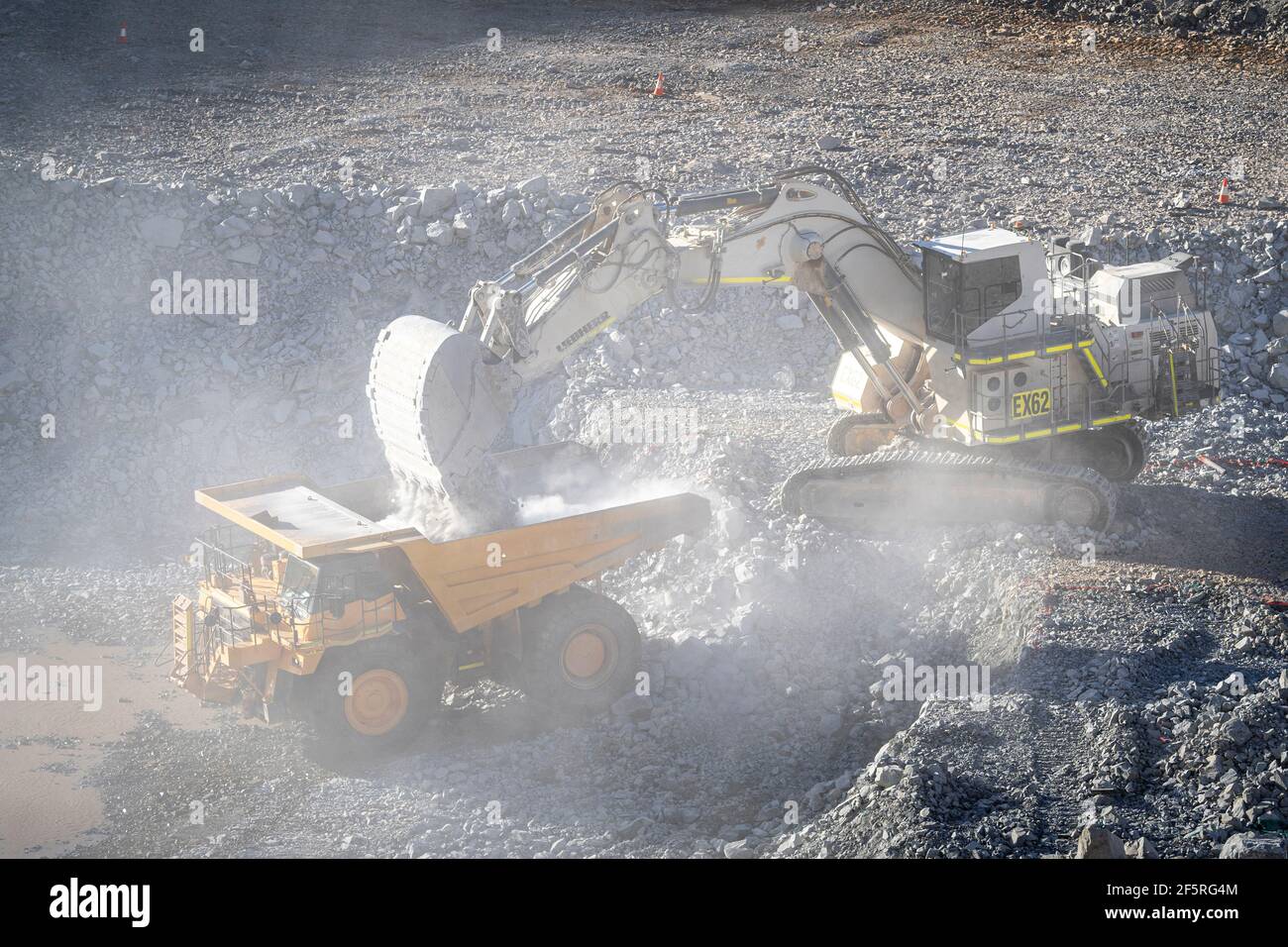 Dusty conditions as digger loads dump truck with ore at gold mine in ...