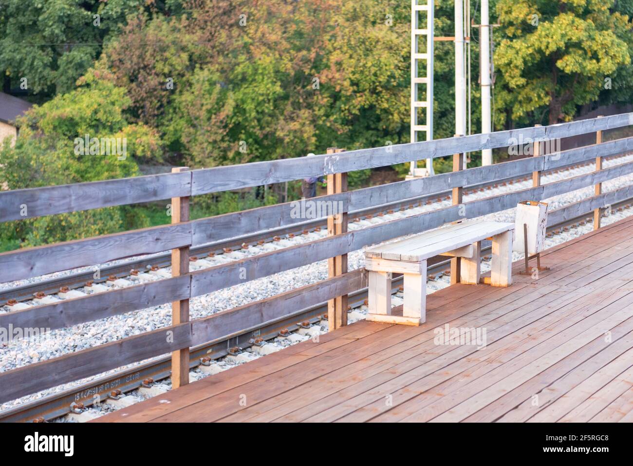 Bench on the railway platform. Wooden platform, bench and fence during ...