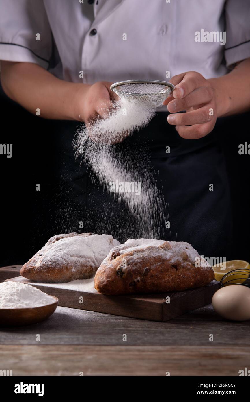 Vertical shot of a female hand pouring powdered sugar through a sieve ...