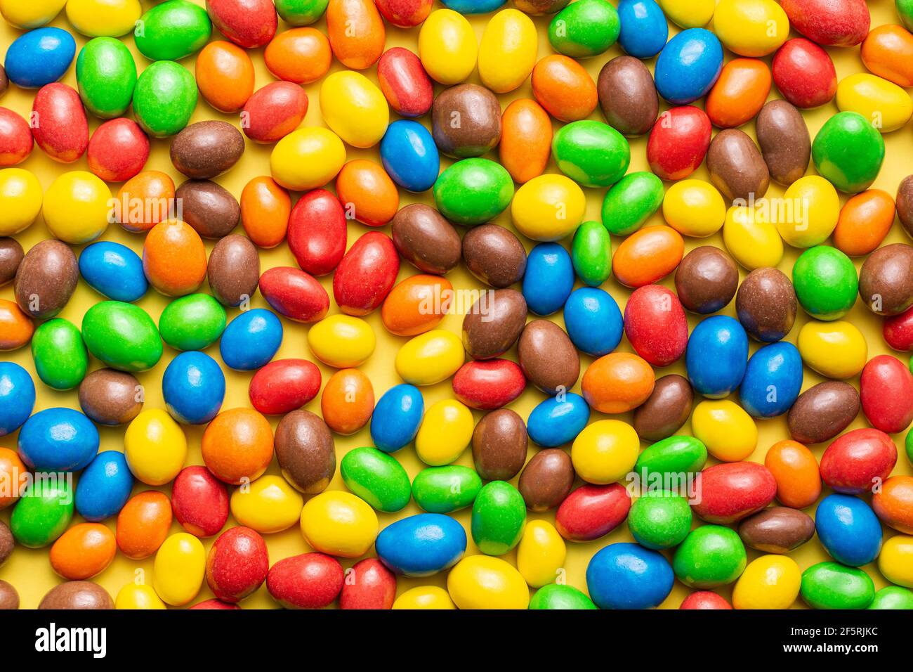 colored crunchy chocolate balls occupying the entire image on a yellow ...