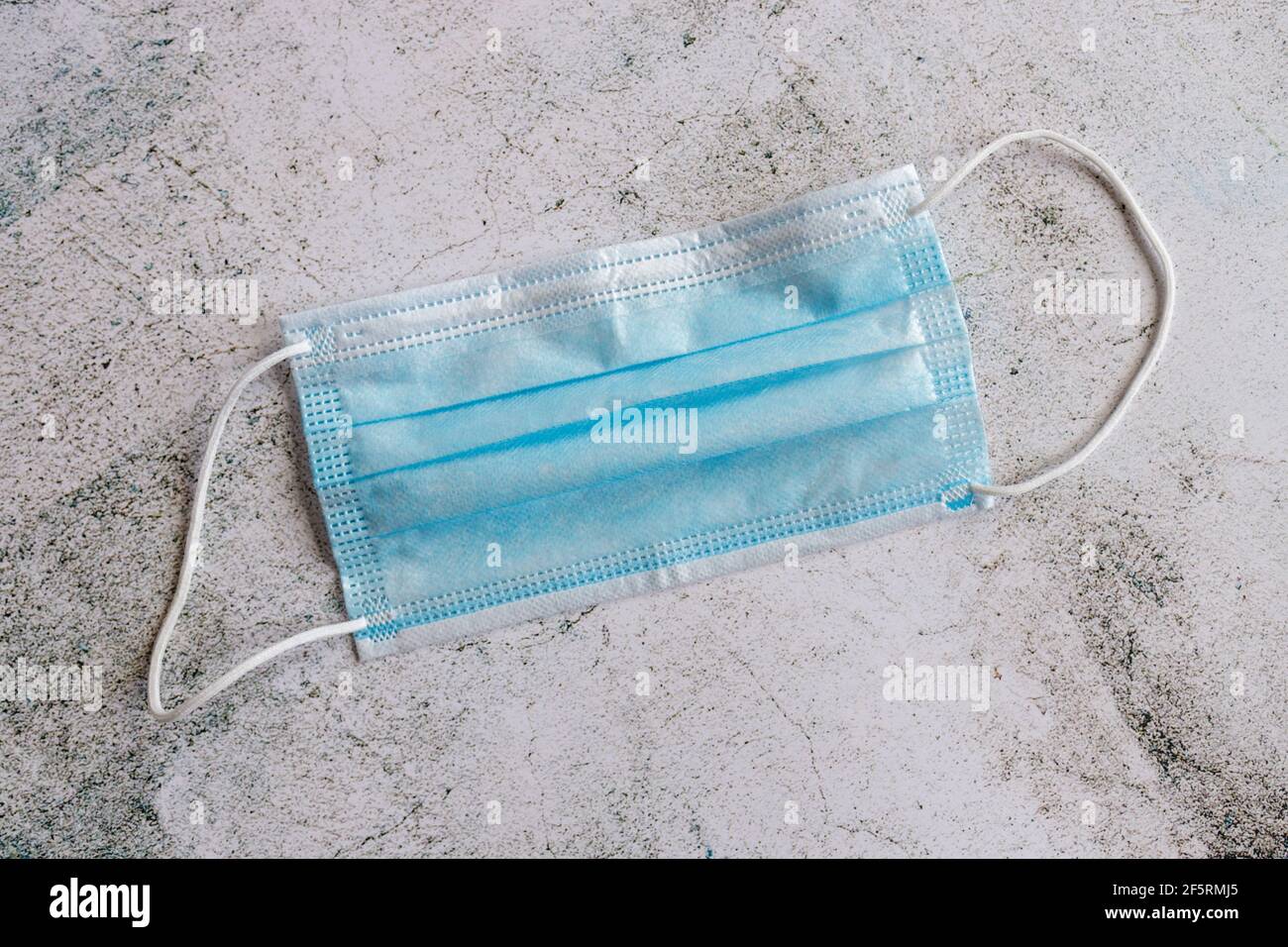 Used surgical face mask isolated on concrete floor. Improperly ...