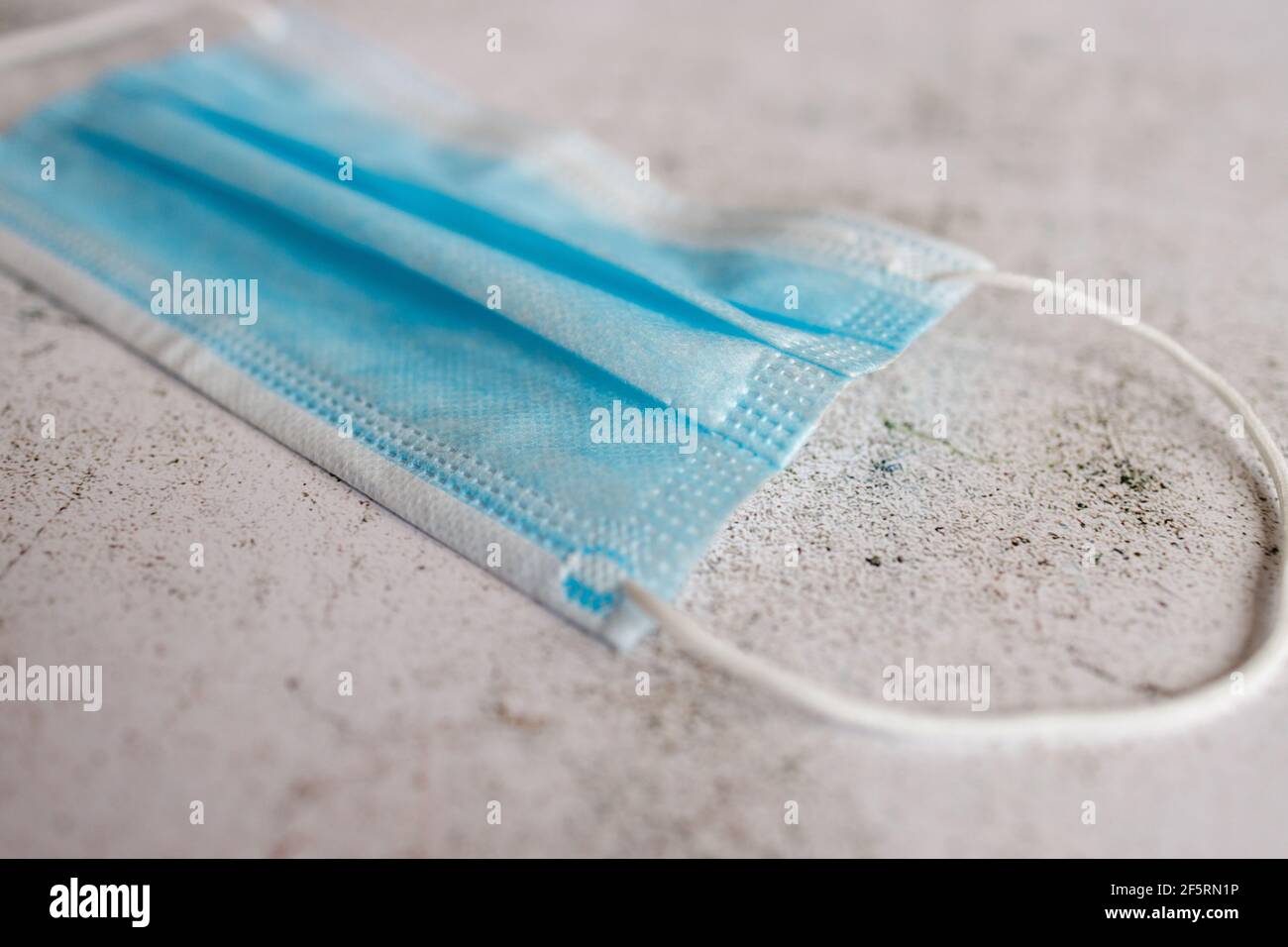 Used surgical face mask isolated on concrete floor. Improperly ...