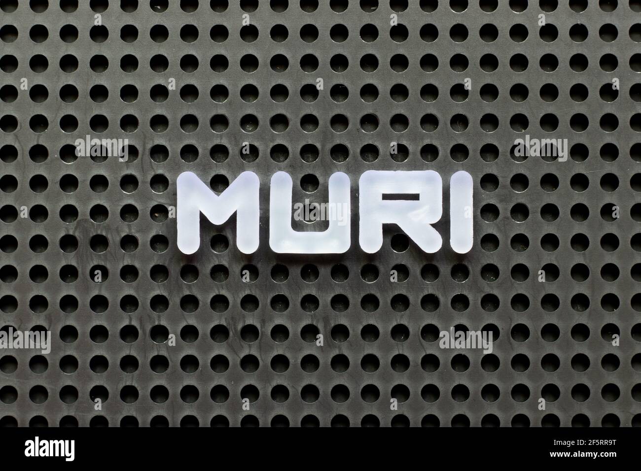 White color letter in word muri on black pegboard background Stock ...