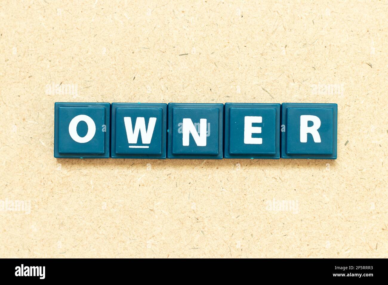 Tile alphabet letter in word owner on wood background Stock Photo - Alamy