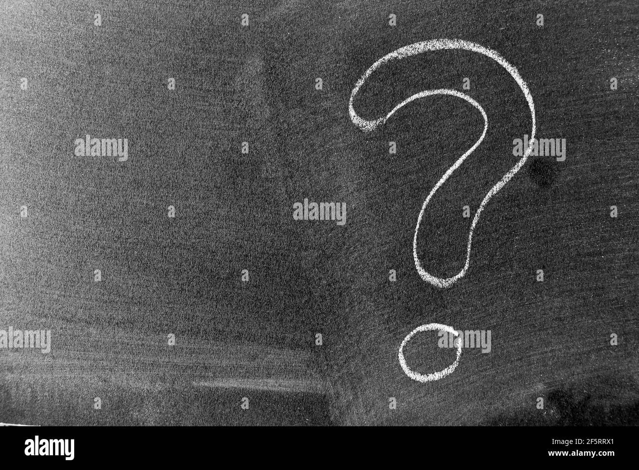 White color chalk hand drawing in question mark shape on blackboard or ...