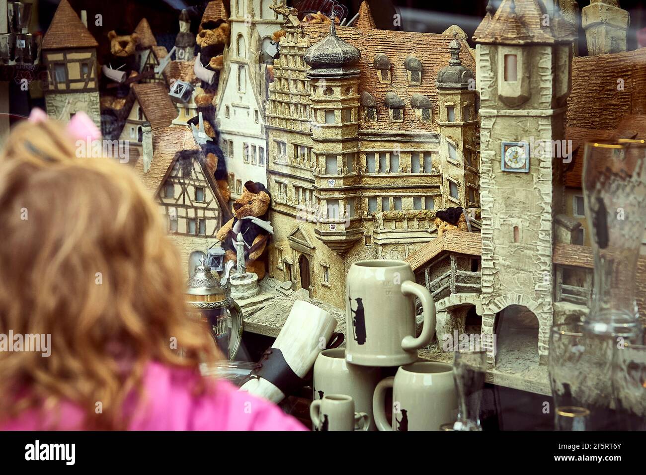 Girl looking through window glass of large toy store filled with ...