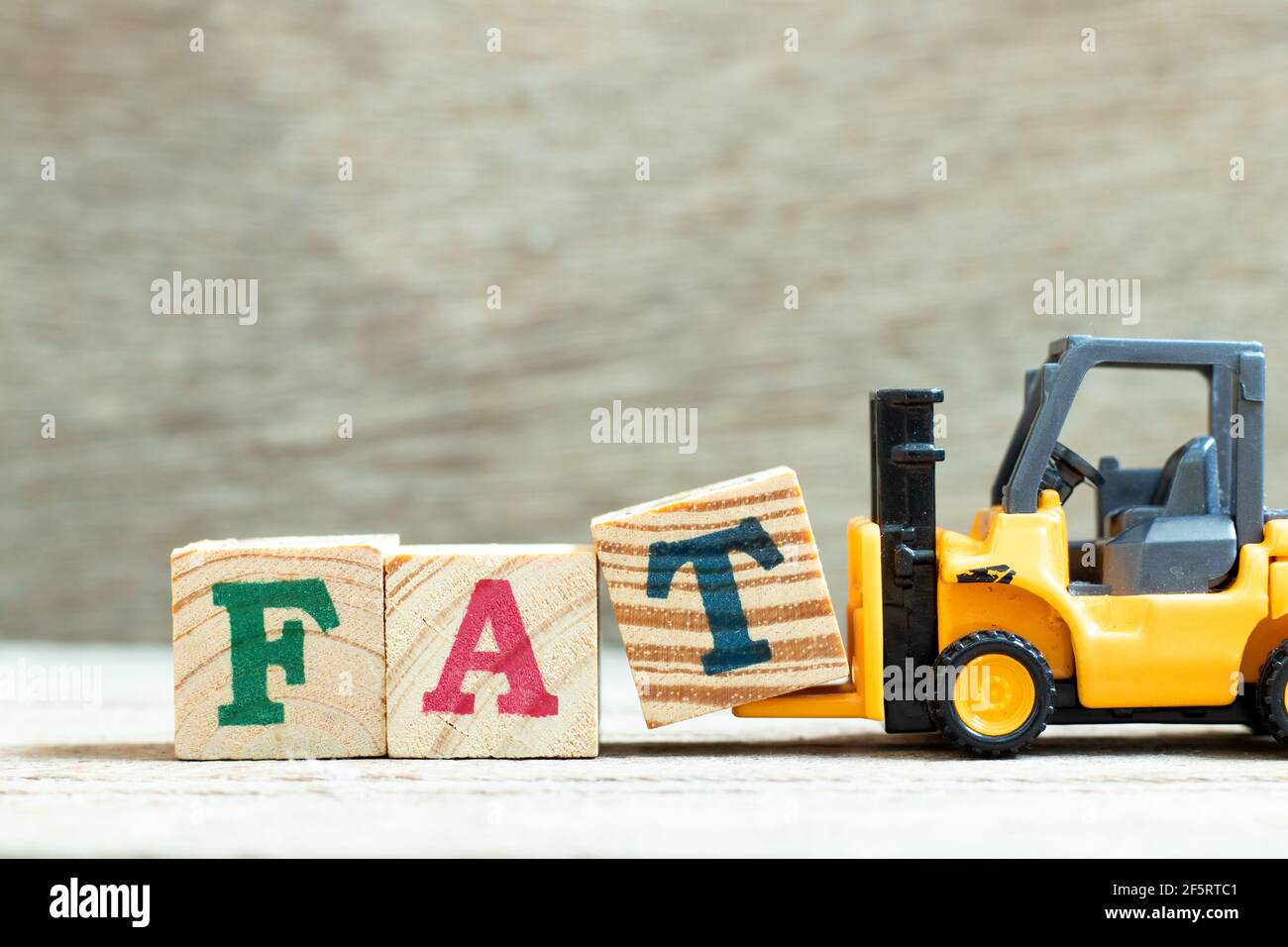 Toy forklift hold letter block T to complete word FAT (Obesity or ...
