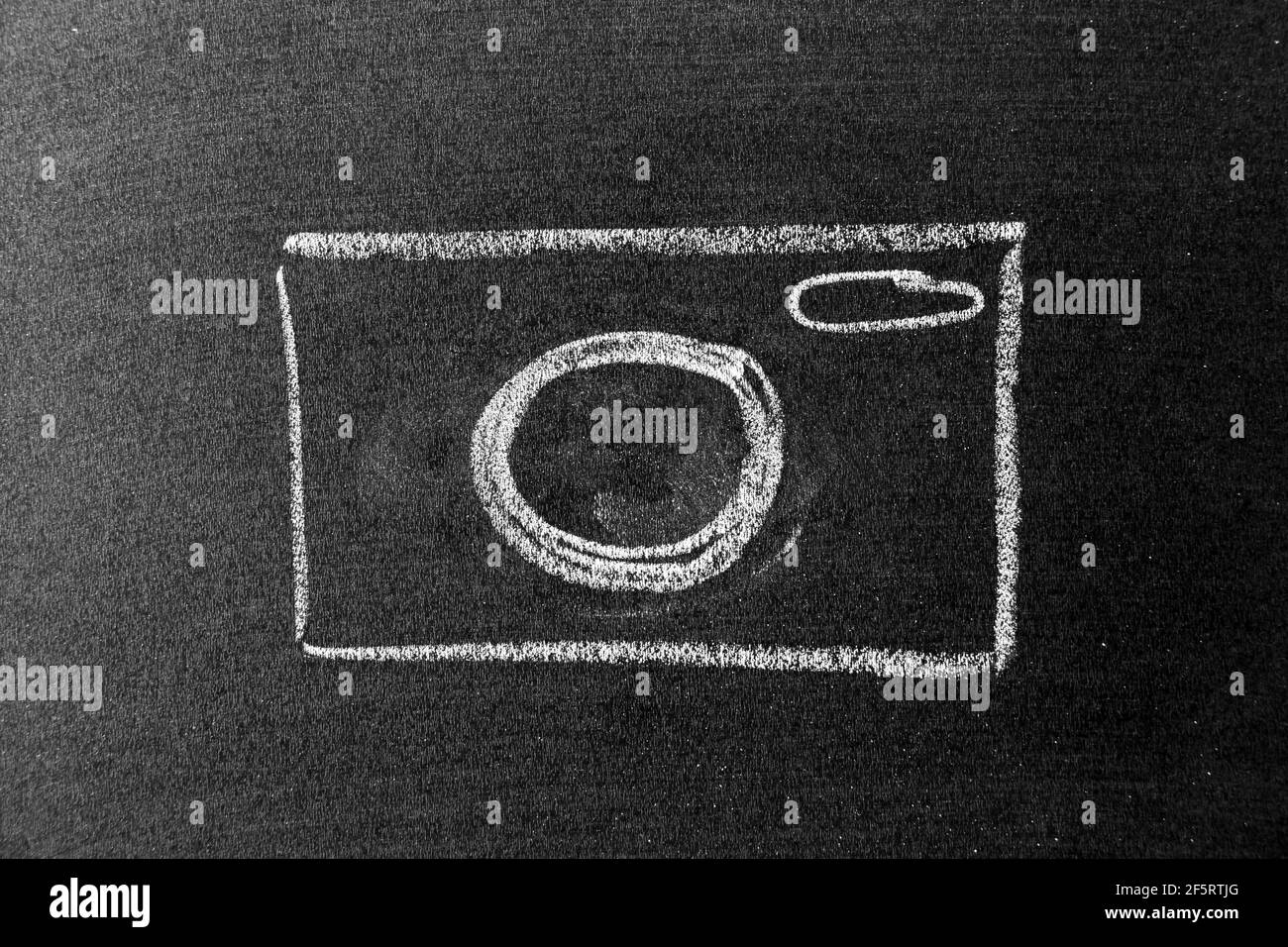 White color chalk hand drawing in camera shape on blackboard or ...