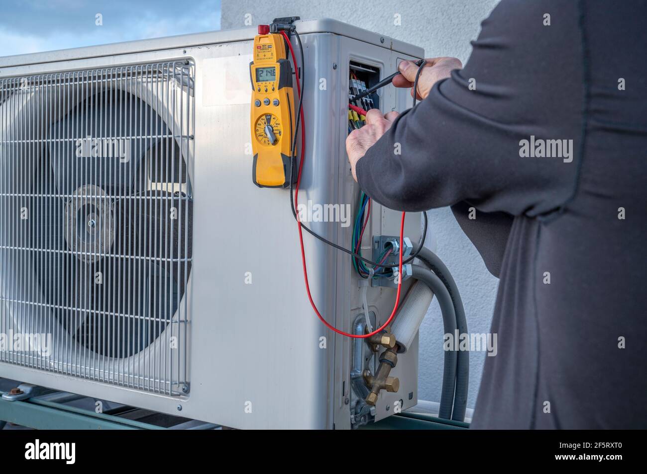Multimeter on mini-split, hands testing voltage with test leads at ...