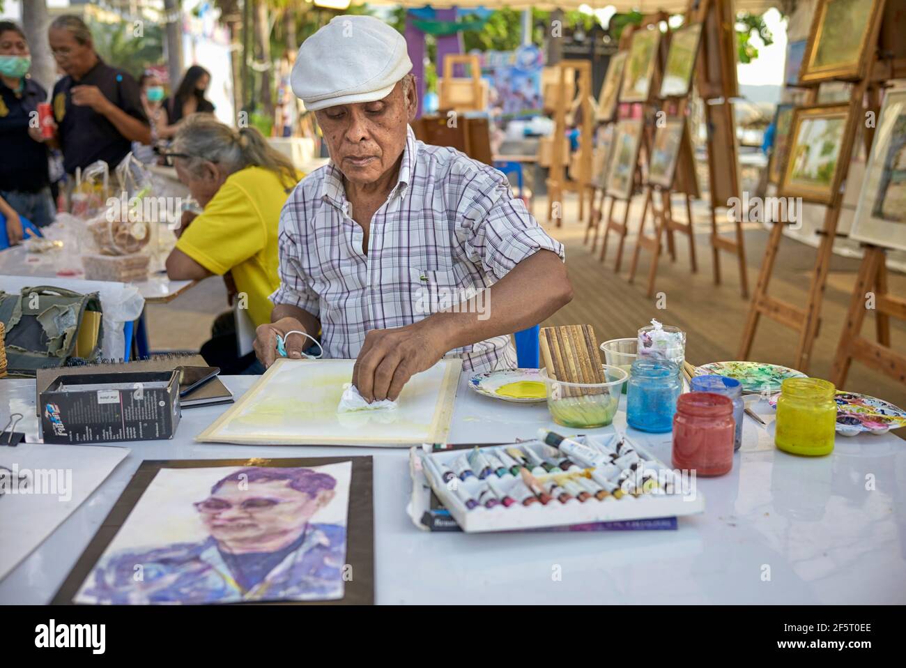 Art fair. Artist working painting a canvas at a street art fair ...
