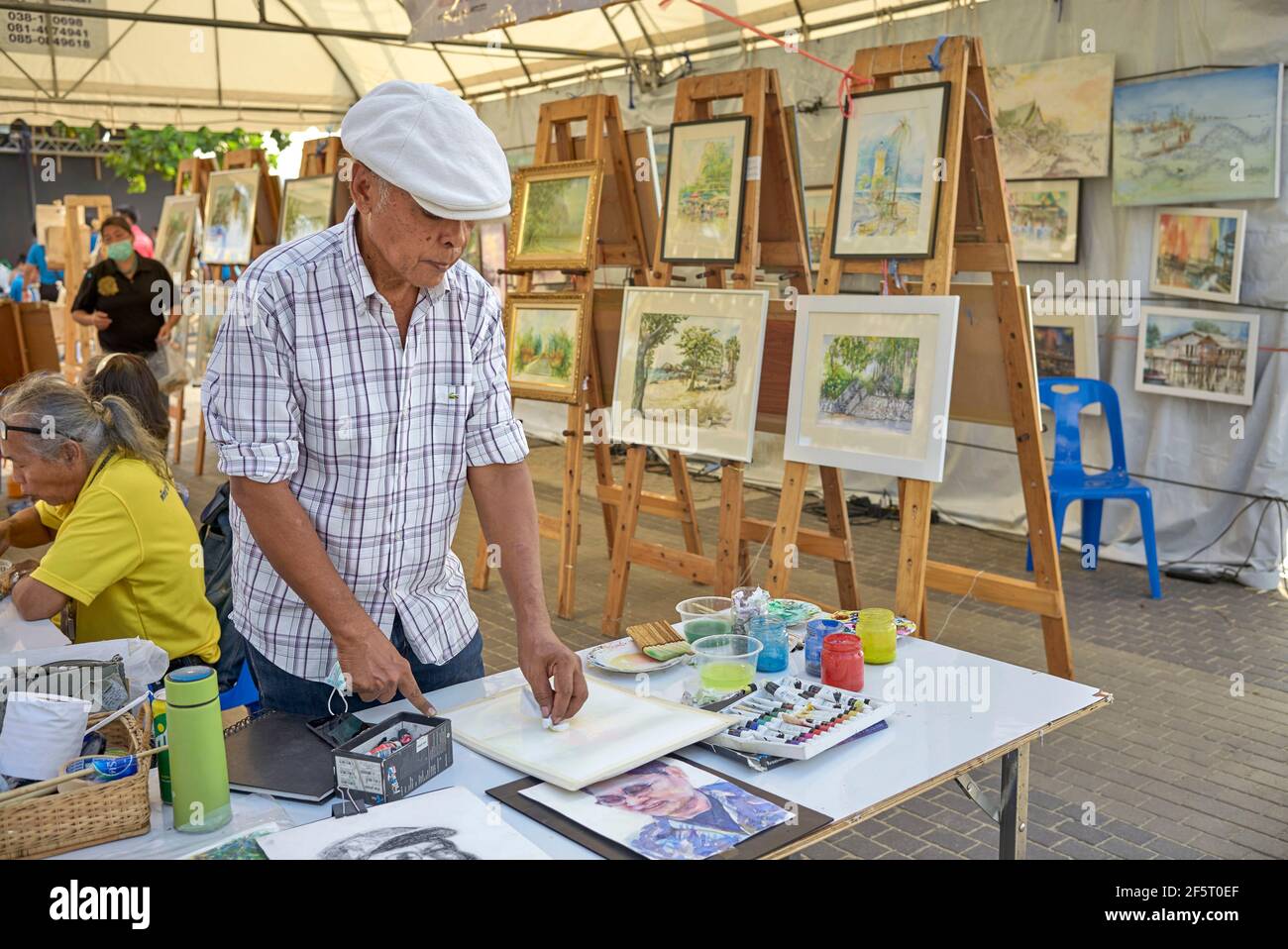 Art fair. Artist working painting a canvas at a street art fair ...