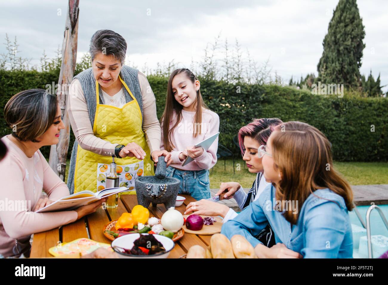 latin grandmother and granddaughter, daughter cooking mexican food at ...