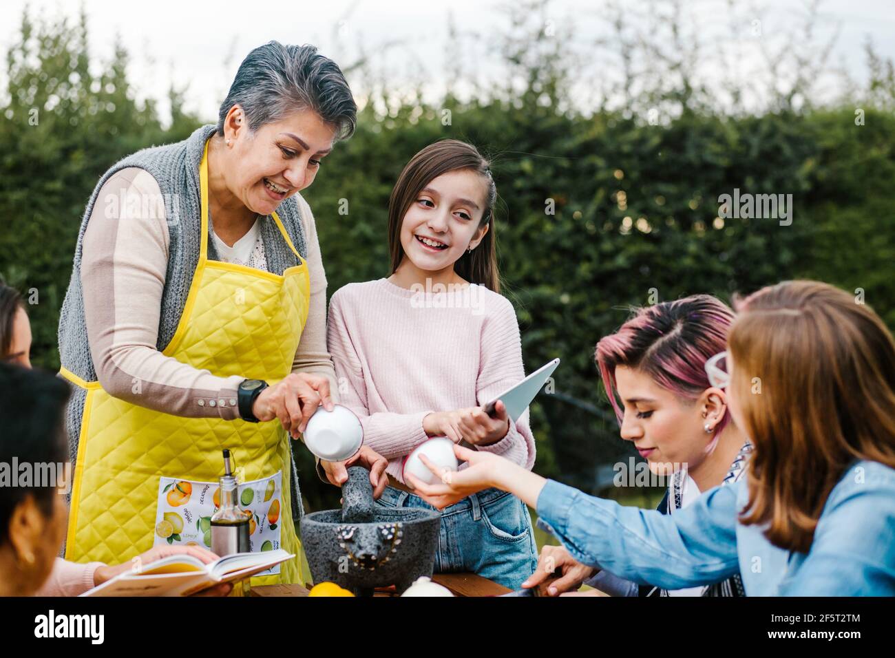 latin grandmother and granddaughter, daughter cooking mexican food at ...