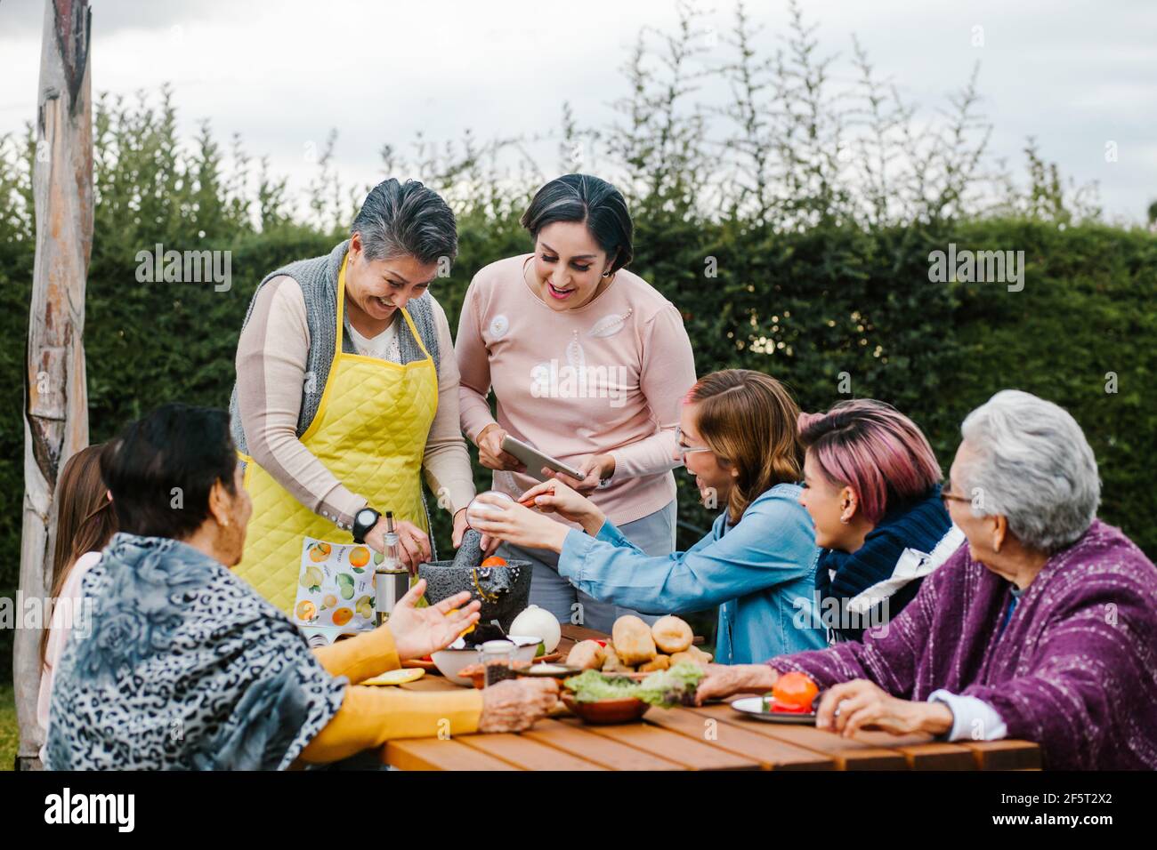 three generations of mexican women grandmother and daughter cooking ...