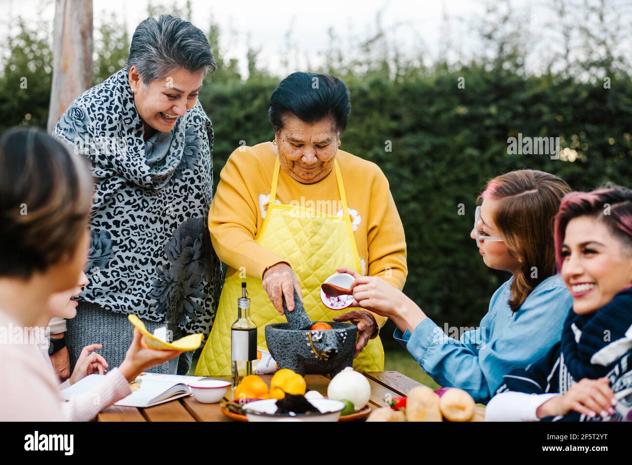 latin grandmother and granddaughter, daughter cooking mexican food at ...