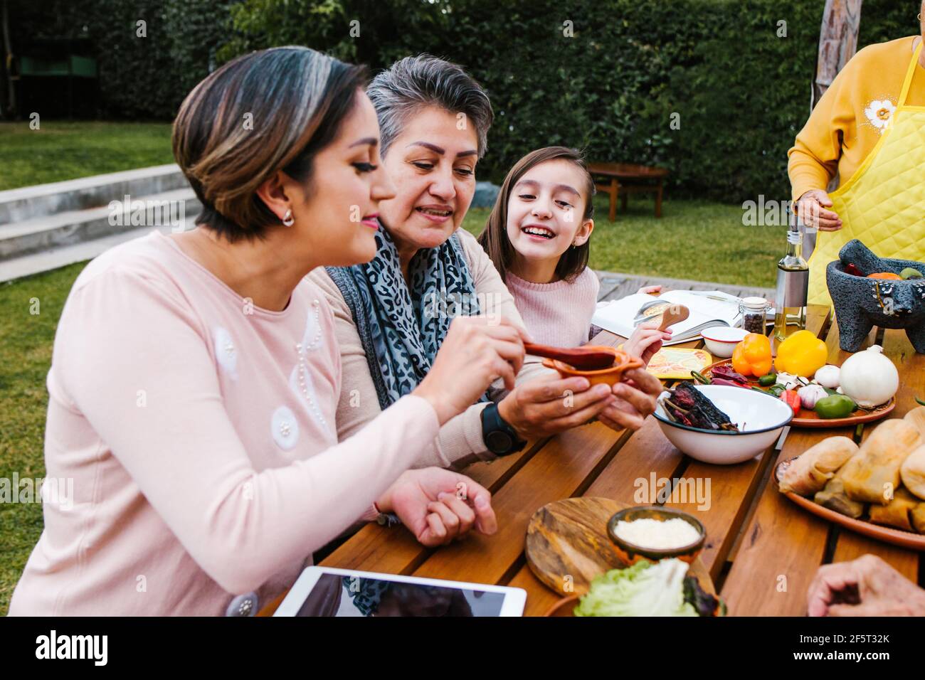 three generations of mexican women grandmother and daughter cooking ...