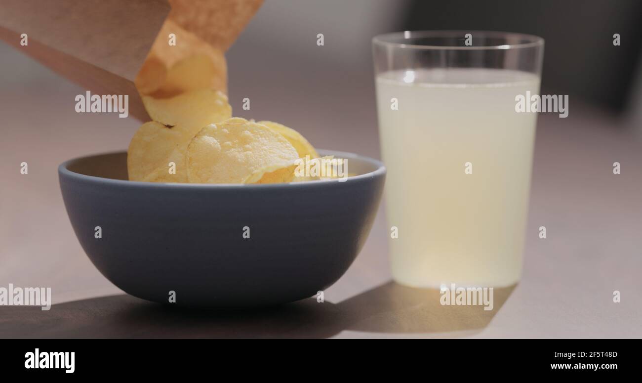 Man hand pour potato chips to blue bowl with ginger beer on background ...