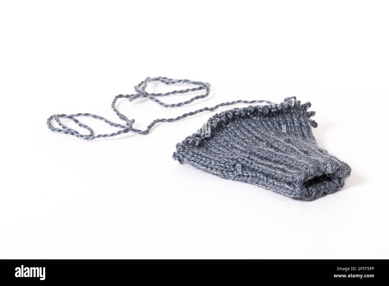Start knitting. Loose mitten isolated on white background Stock Photo ...
