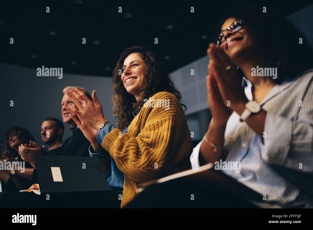 Audience listening to the speech and clapping hands. Group of business ...