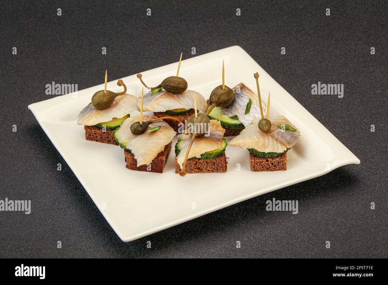 Herring fillet canape snack with caperberry and cucumber Stock Photo ...