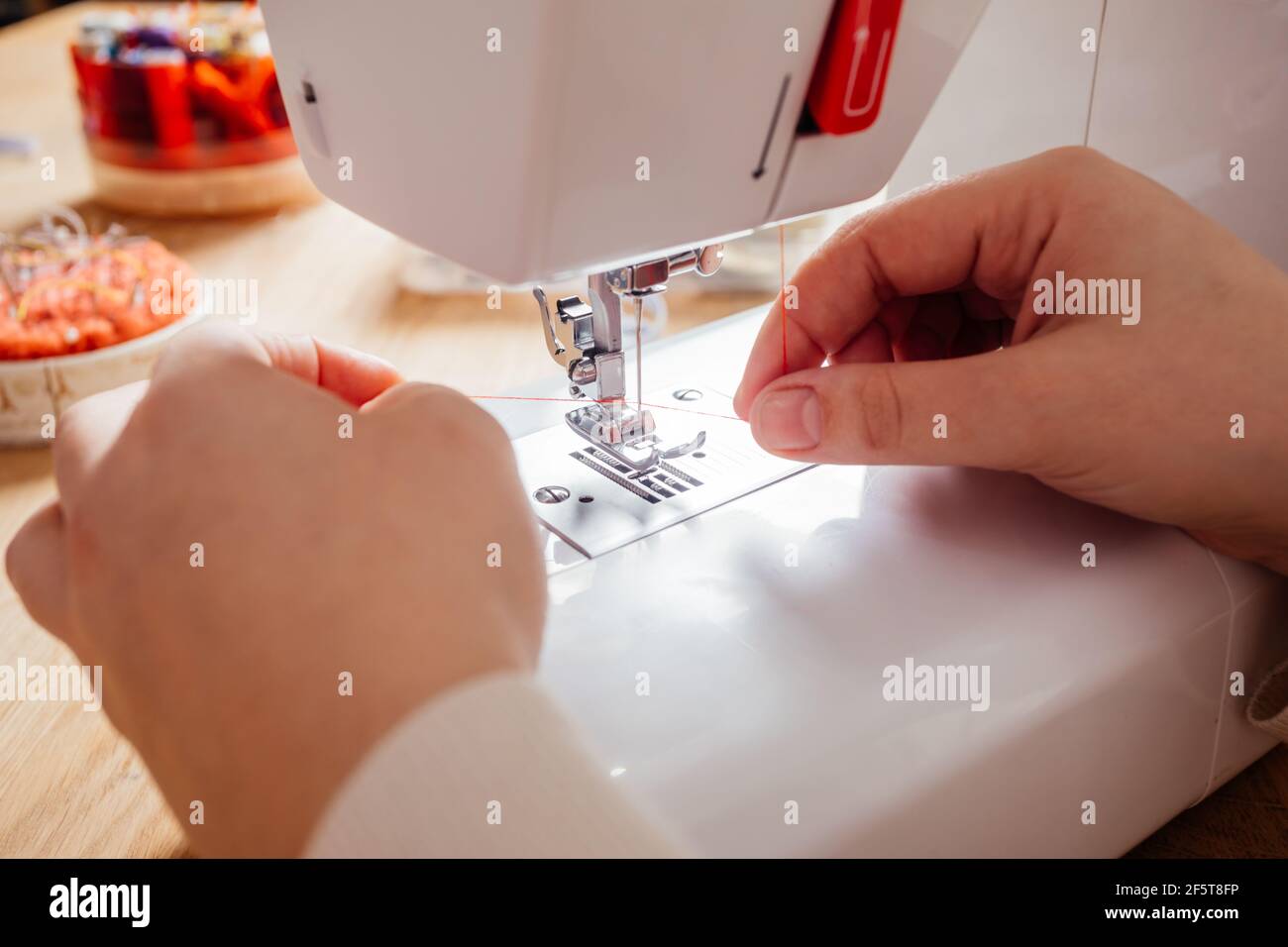 Closeup hands inserting thread into sewing machine needle Stock Photo ...
