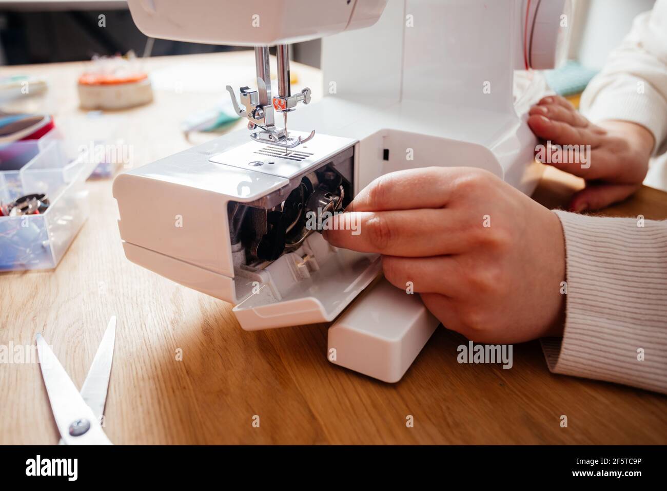 Putting the metal spool into sewing machine Stock Photo - Alamy