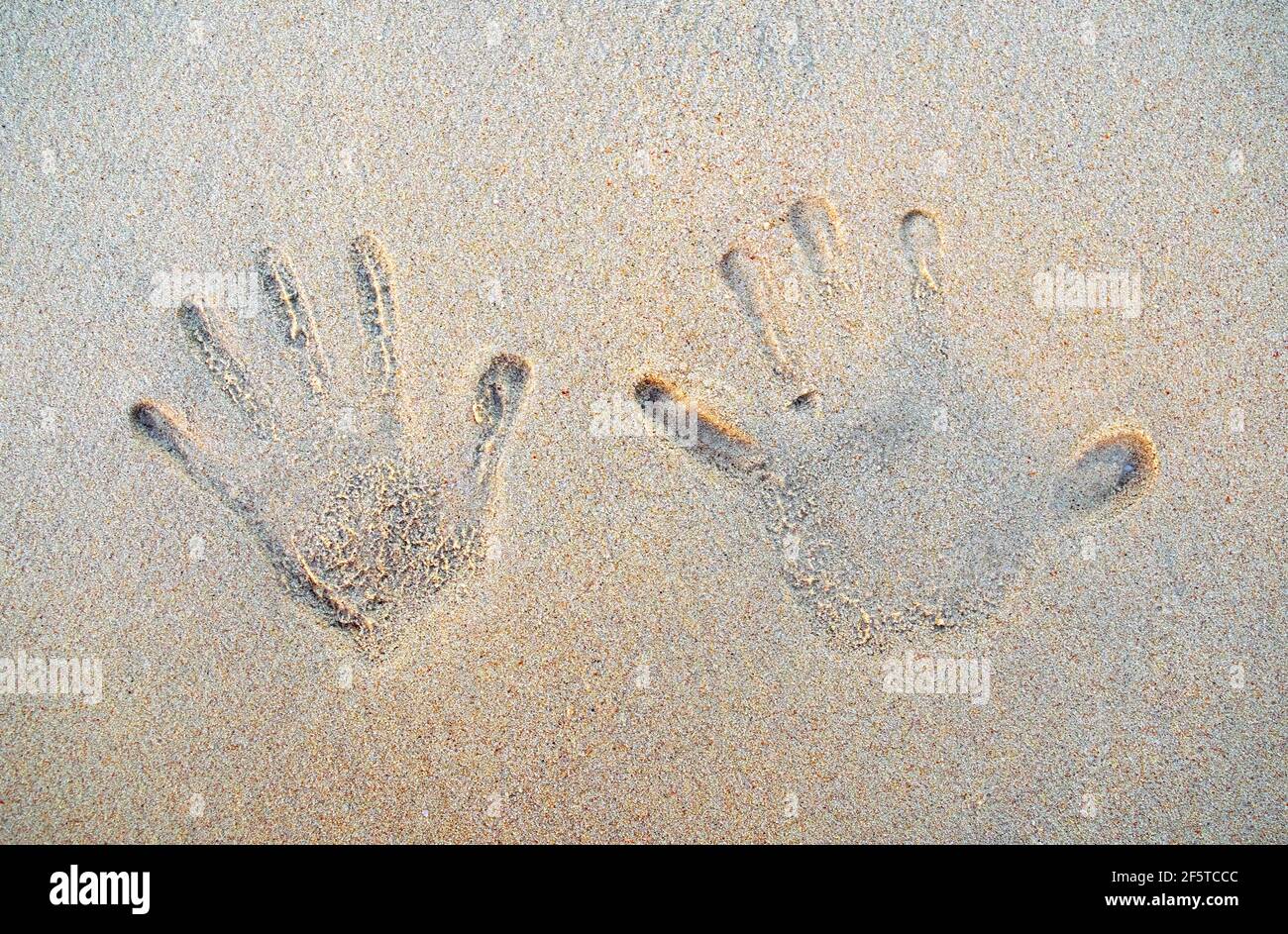 Hand's prints on the sand of the beach with sea waves. Top view. Two ...
