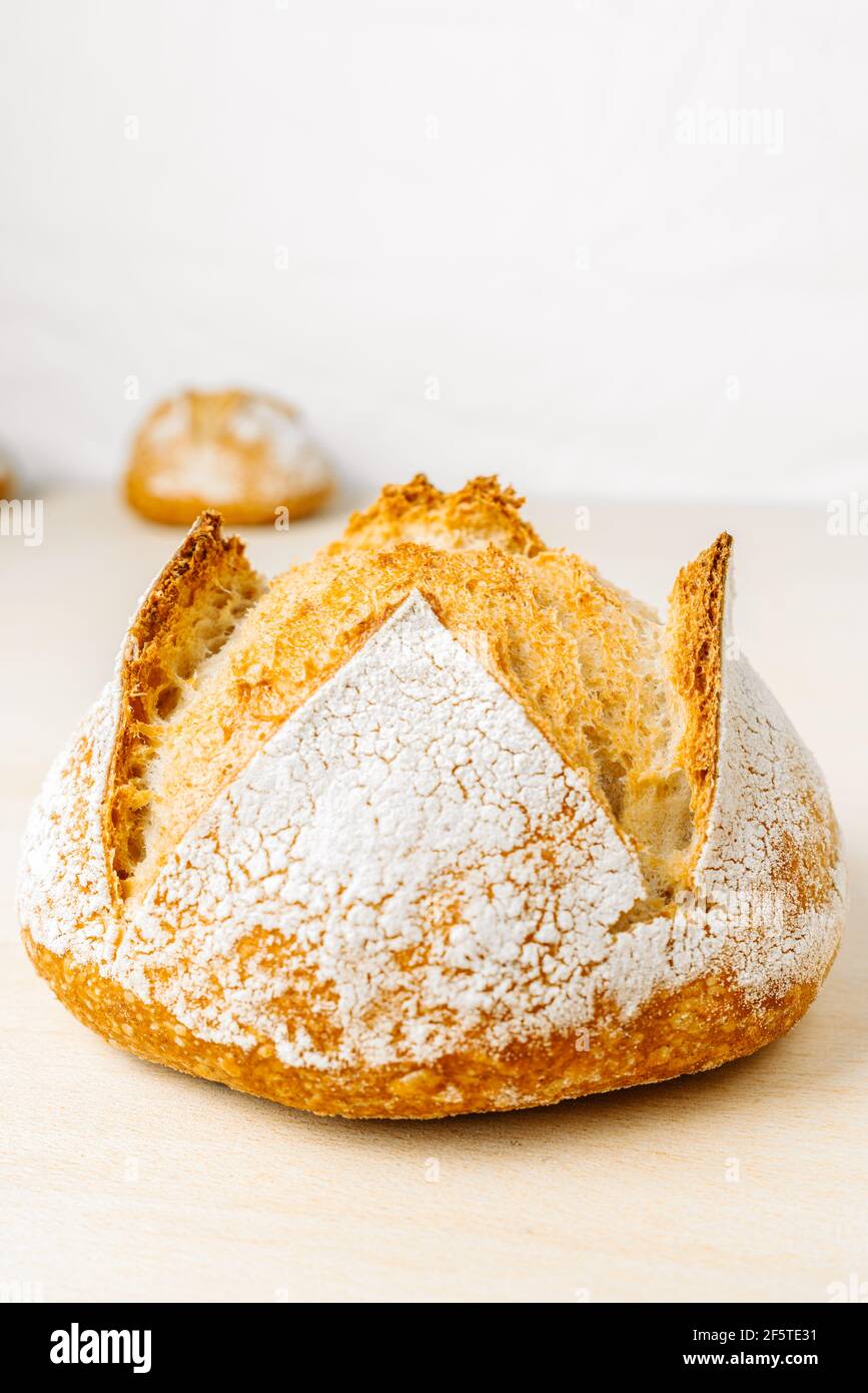 Delicious round shaped bread with flour on golden surface in bakery on ...