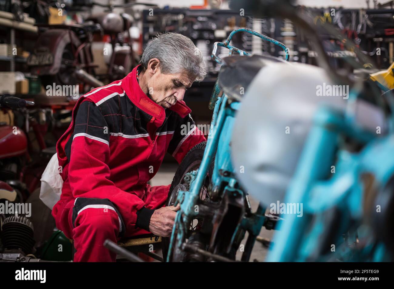 Side view of serious skilled elderly male mechanic in workwear ...