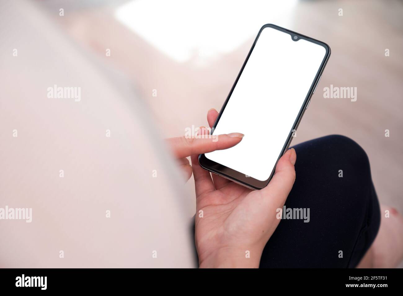 Over shoulder shot of woman using a phone with blank white screen ...