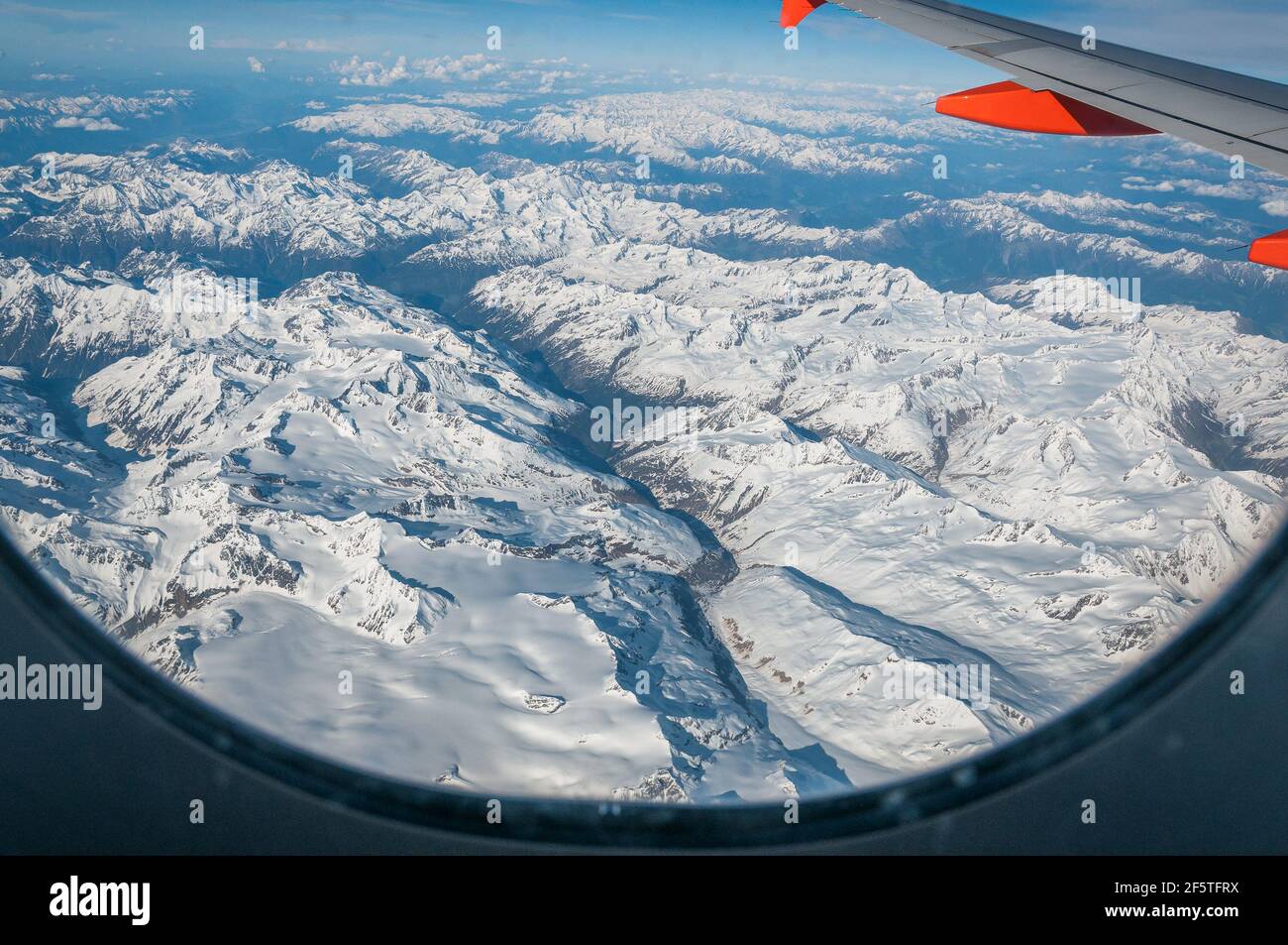 View of the snow-capped Alps from an airliner porthole. Concept: air ...