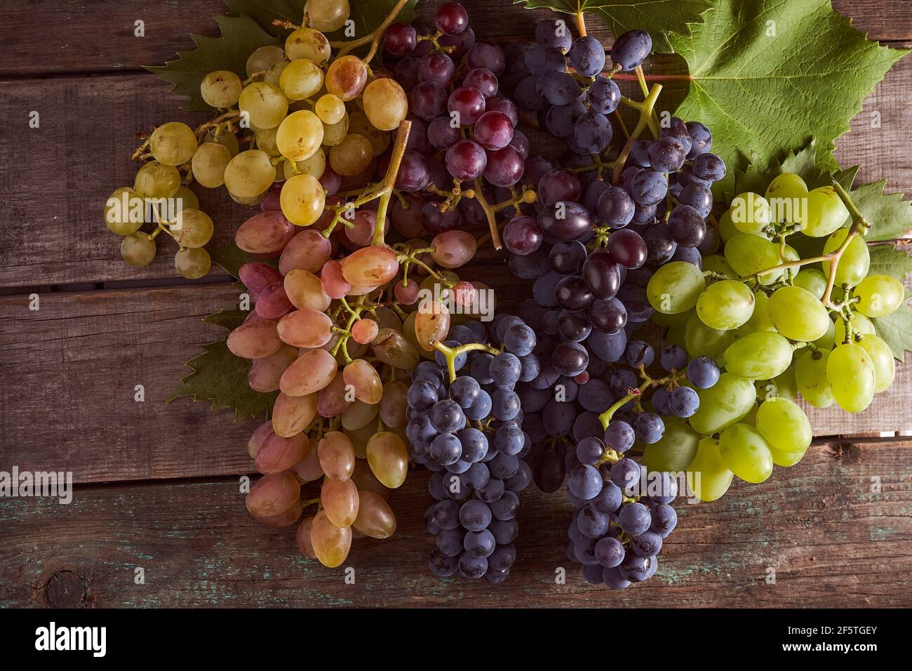 Different varieties of grapes on a wooden table Stock Photo - Alamy