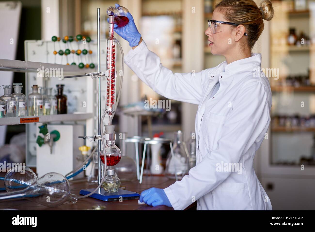 A young female scientist using an apparatus for the experiment in a ...