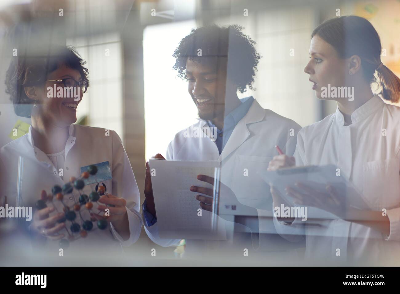 Young colleagues taking the notes about chemical bonds explained on a ...