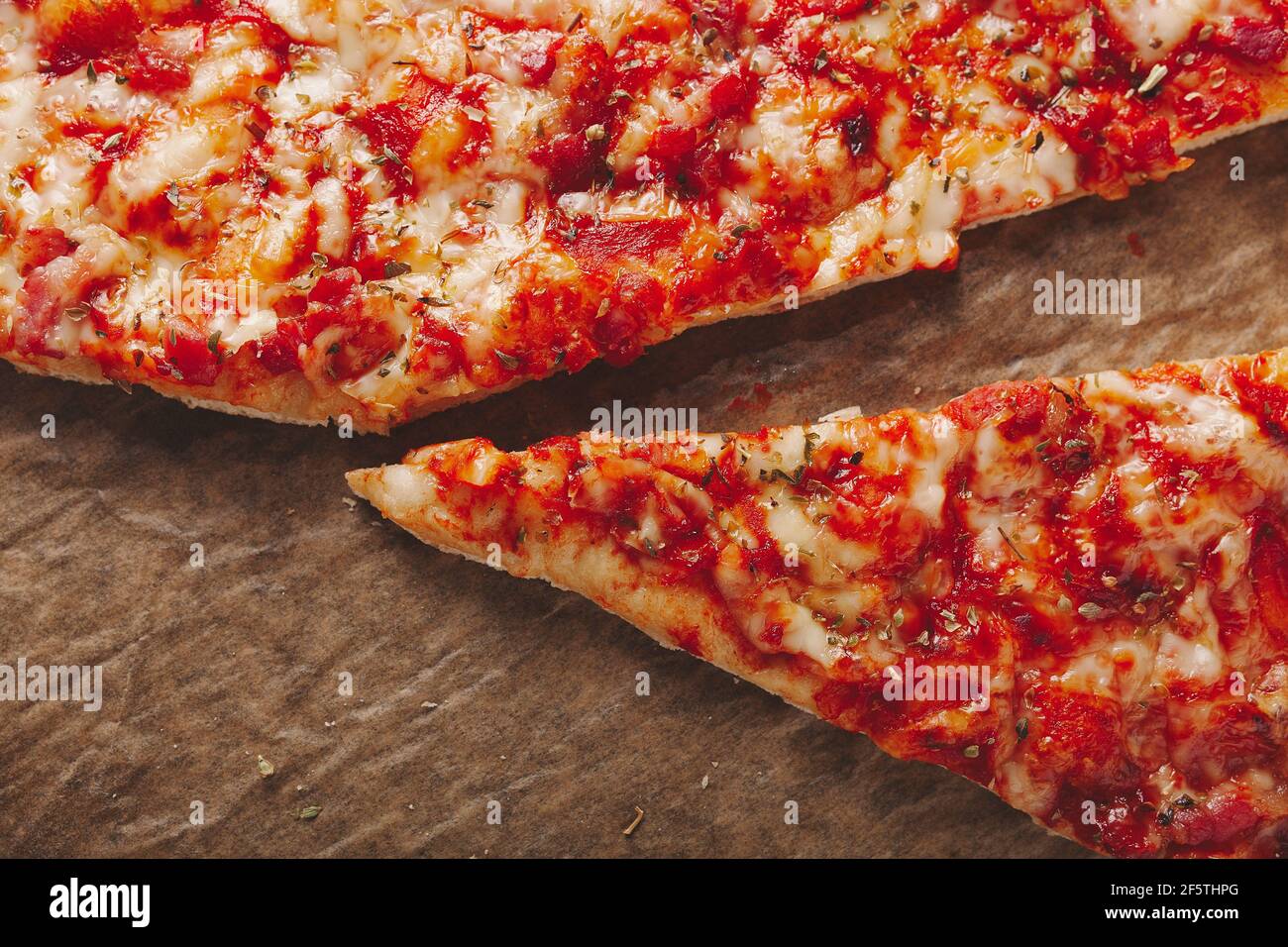 Homemade pizza with triangle slice laying on a brown baking paper Stock ...