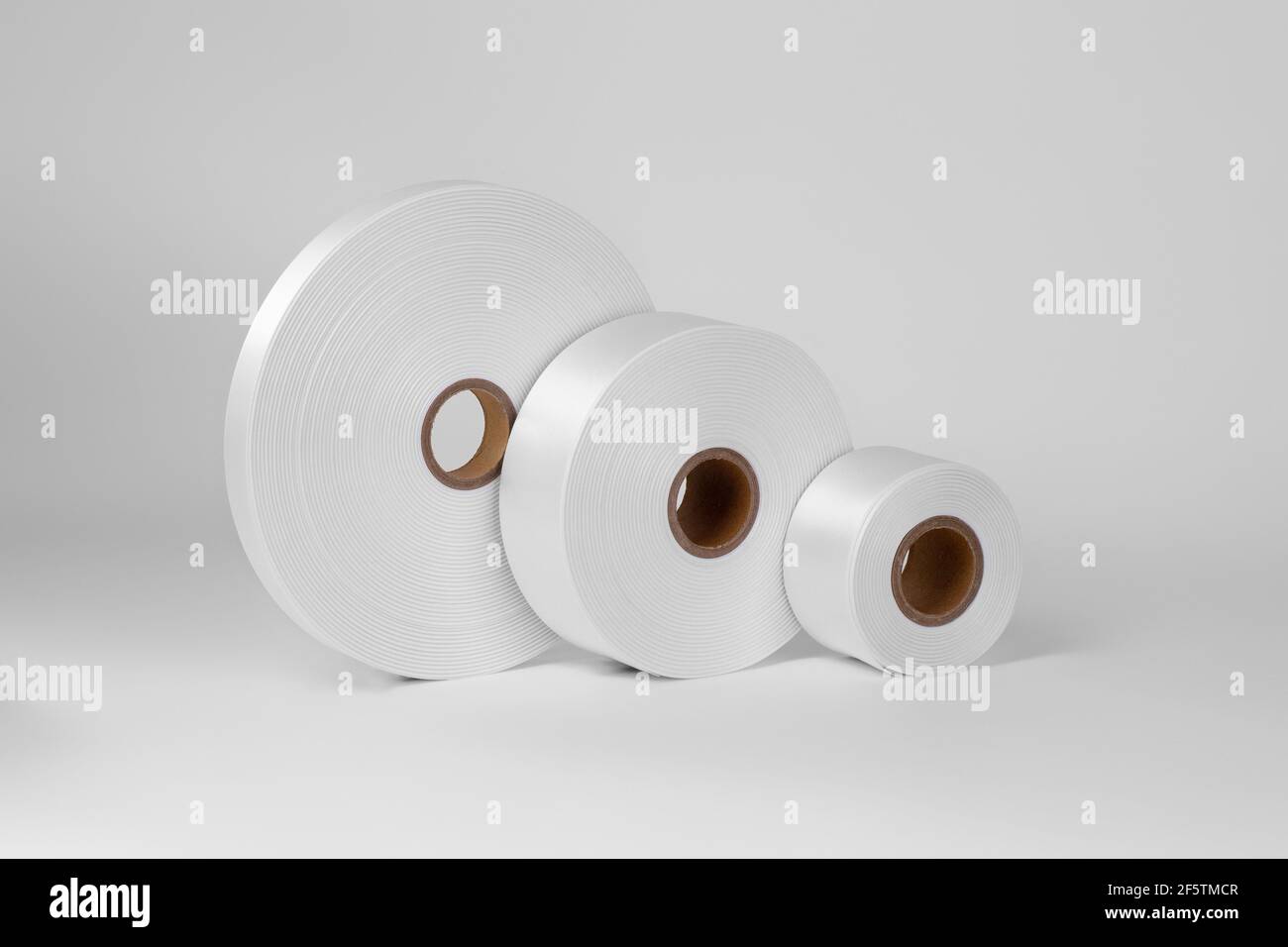 Side view a tower of three coils of white satin ribbons of different ...