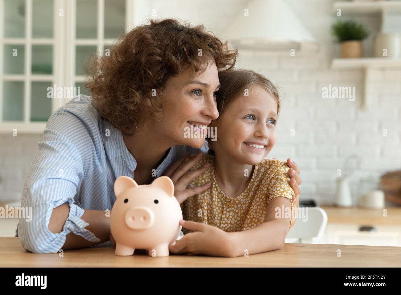 Smiling mom and small daughter saving for future Stock Photo - Alamy