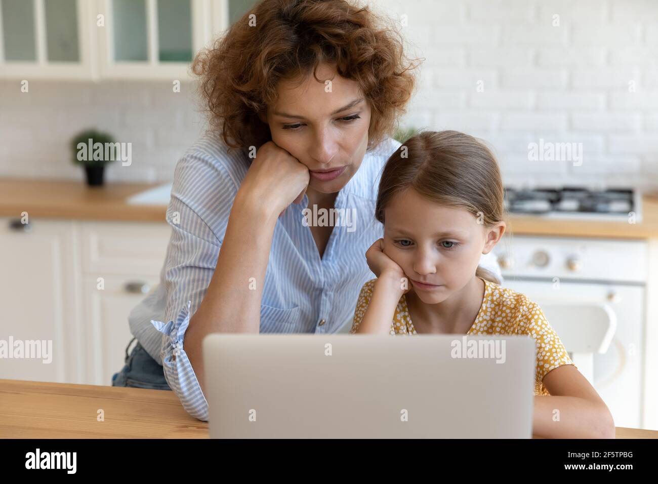 Pensive mom and little daughter use computer thinking Stock Photo - Alamy
