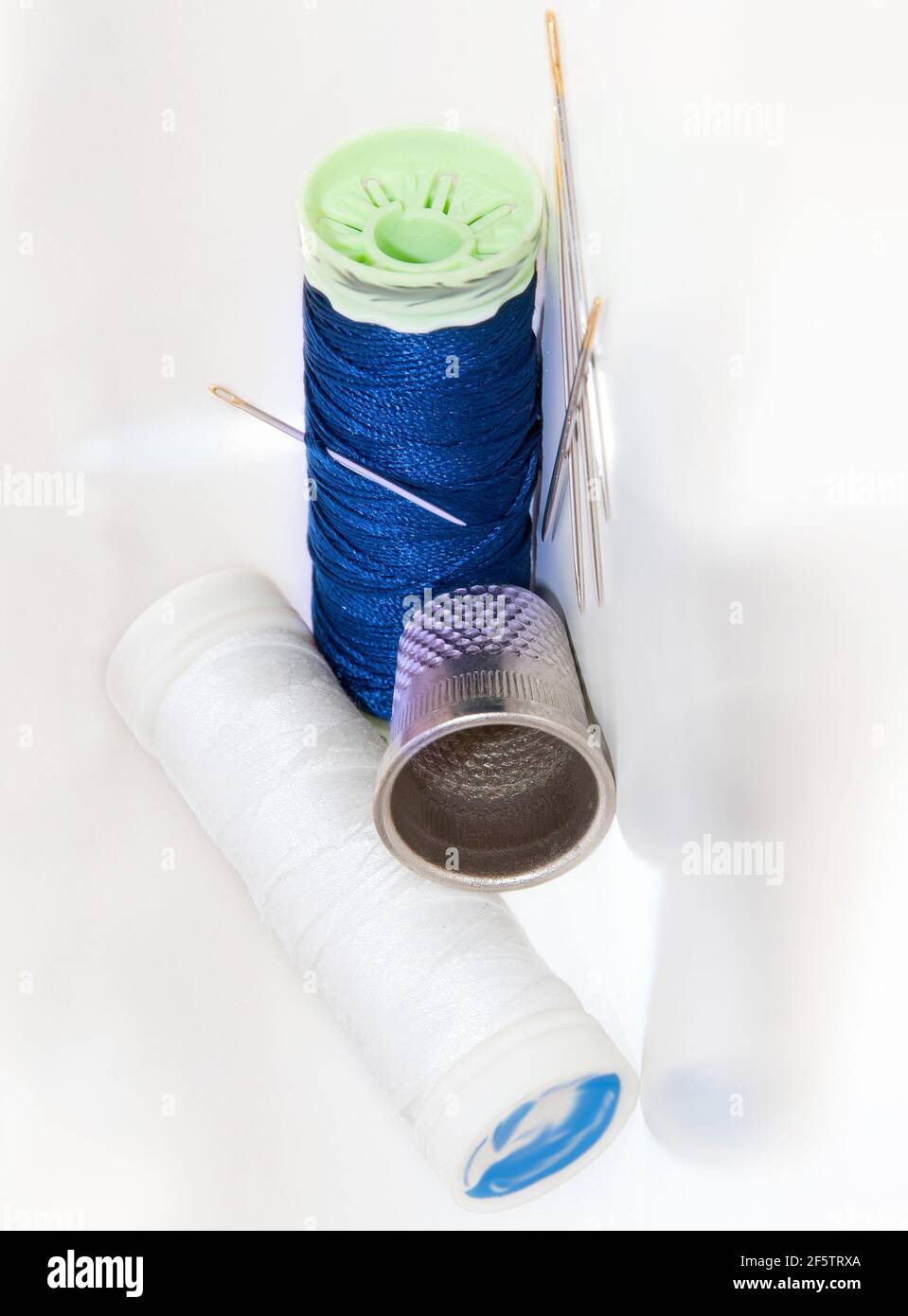 Close-up photo of White and blue thread spools with needles and sewing ...