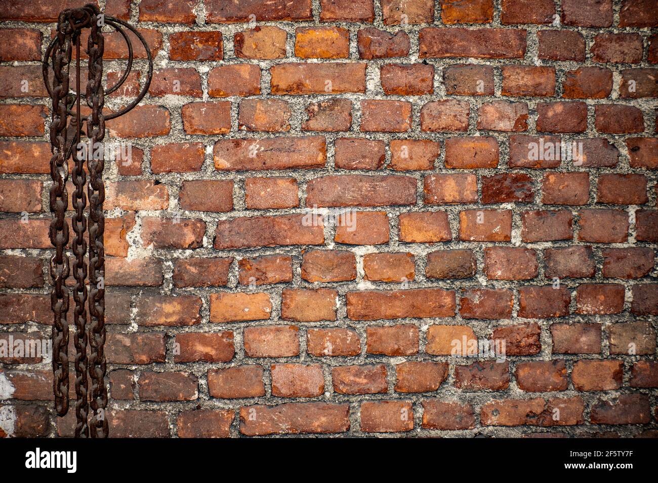 An old rusty chain hanging on a brick wall Stock Photo - Alamy