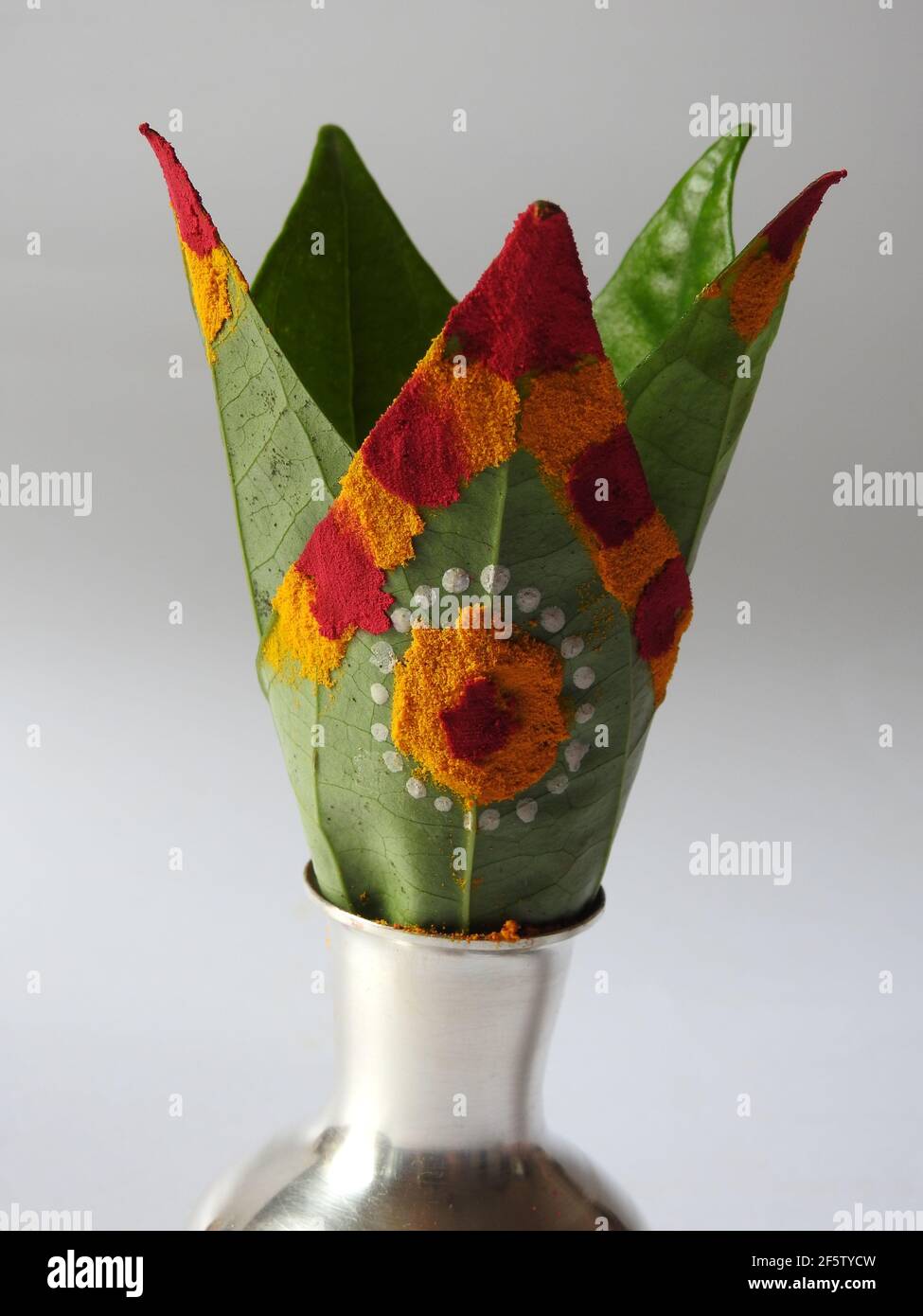 A silver Kalash with leaves, kumkum, turmeric, ganesha, and lakshmi ...