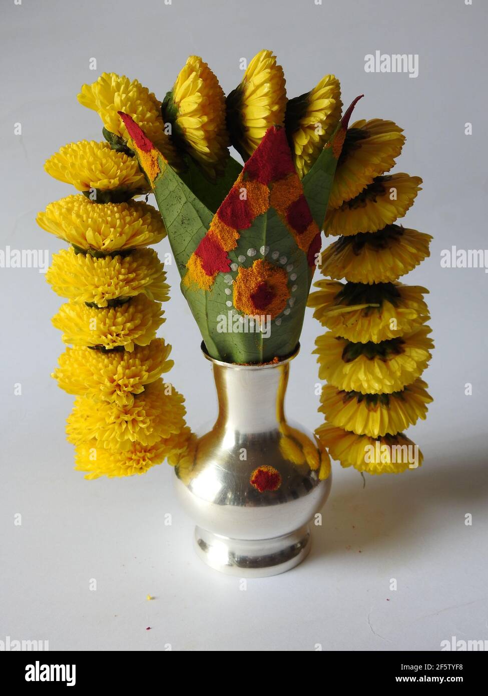 A silver Kalash with chrysanthemum flowers, leaves, kumkum, turmeric ...